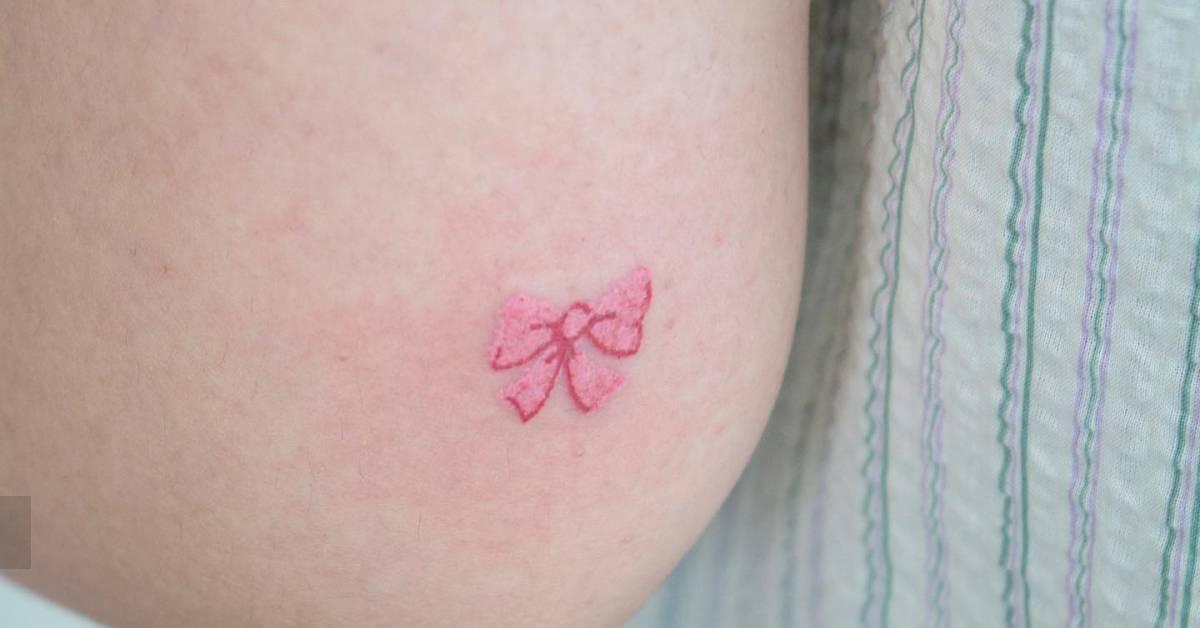 Pink bow tattoo in watercolor style located on the