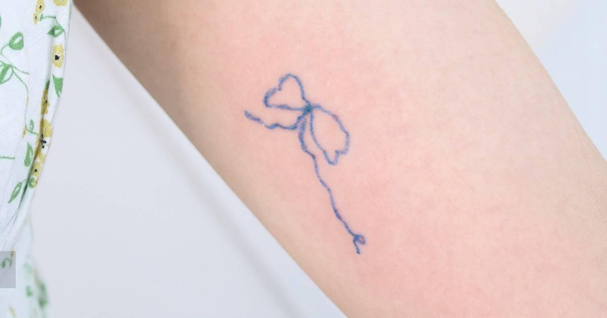 Blue ribbon tattoo located on the inner arm, watercolor