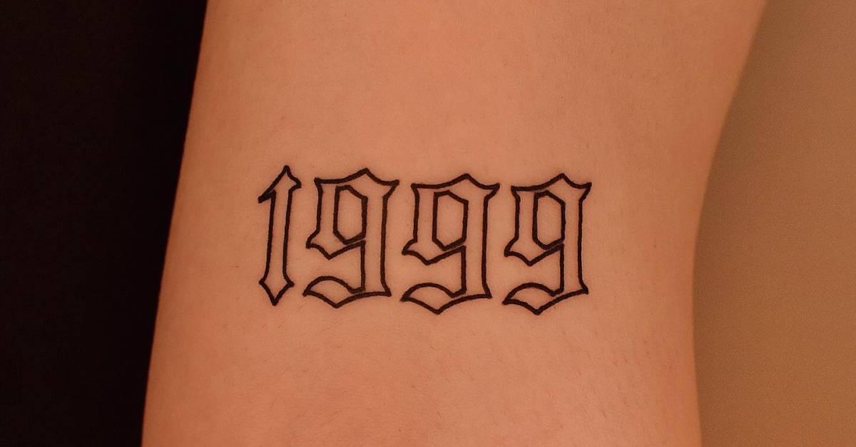 "1999" lettering tattoo in gothic font located on the