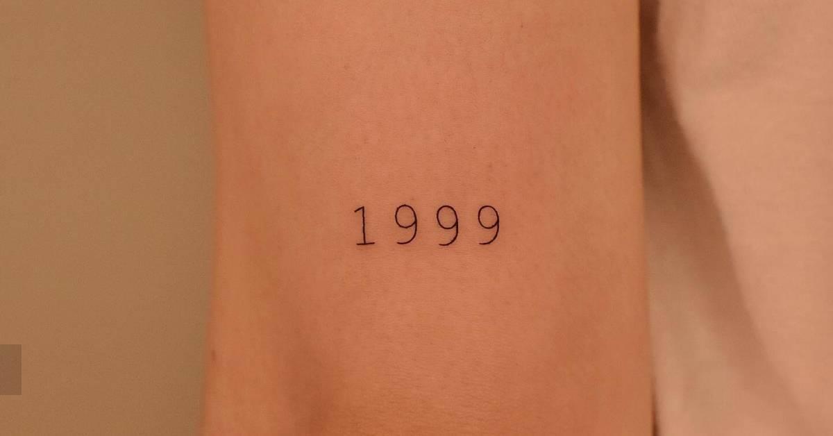 "1999" lettering tattoo placed on the tricep.