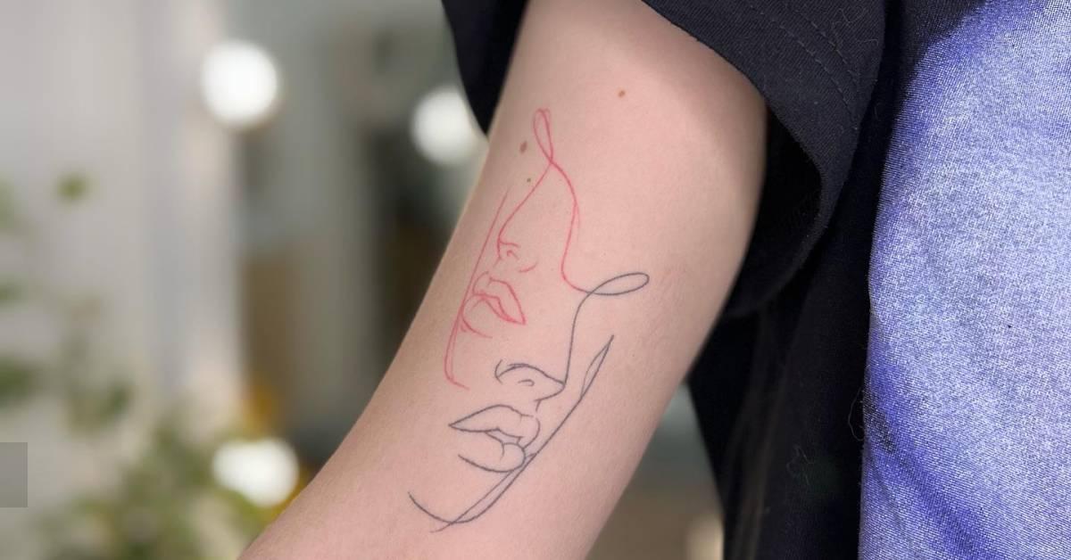 Healed fine line style faces tattooed on the bicep.