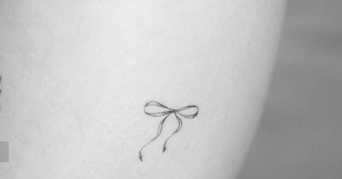 Fine line style ribbon bow tattooed on the calf.