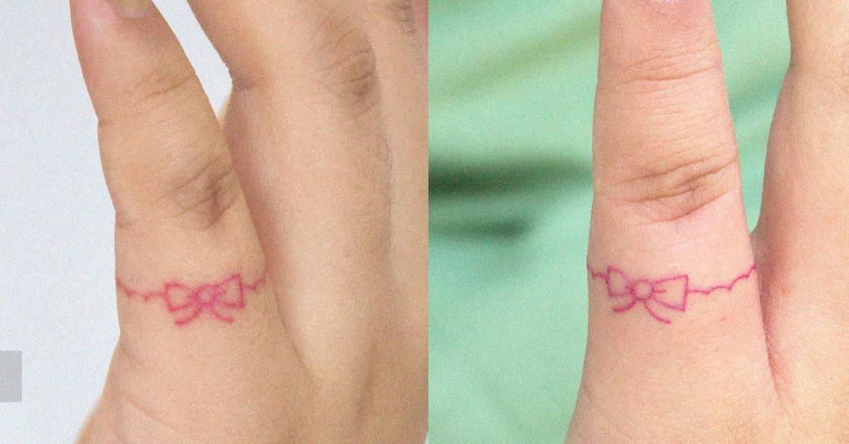 Fresh and healed pink bow ring tattooed on the finger.