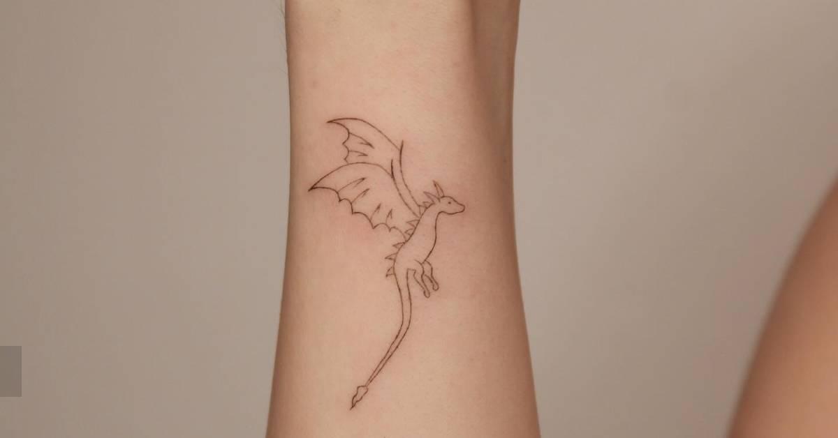 Fine line style dragon tattoo located on the wrist.