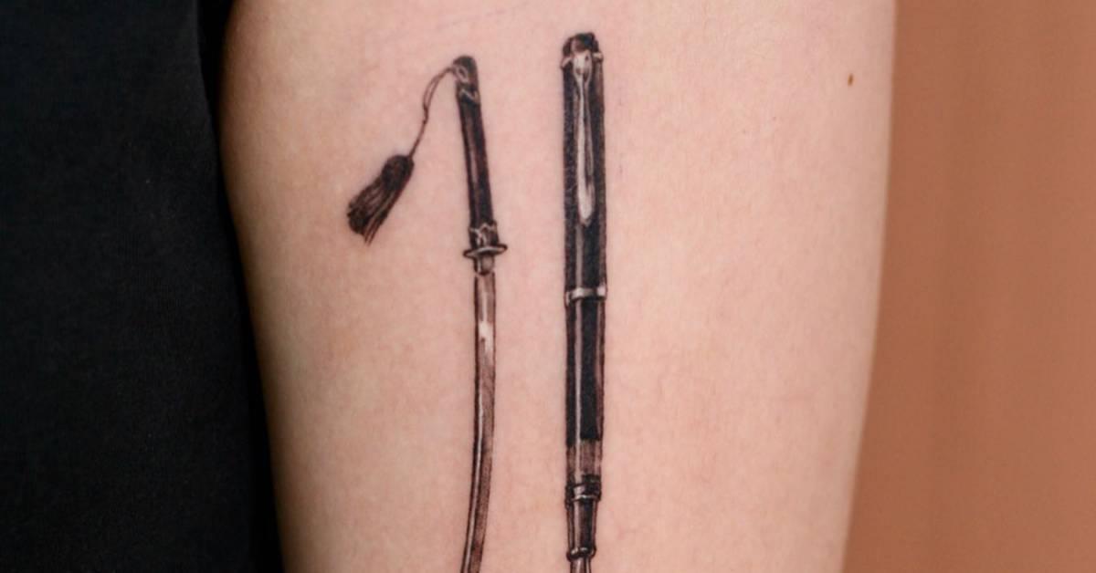 Micro-realistic katana sword and pen tattoo located on