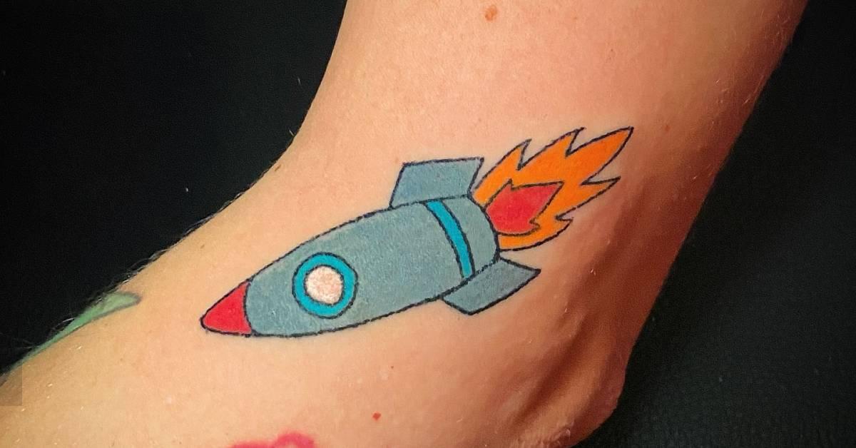 Cartoon style rocket tattoo hand poked on the elbow.