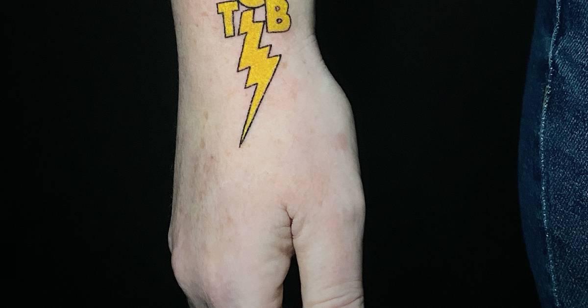 TCB band logo tattooed on the wrist.