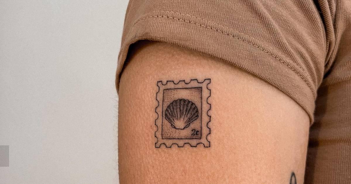 Scallop shell stamp tattoo located on the upper arm.