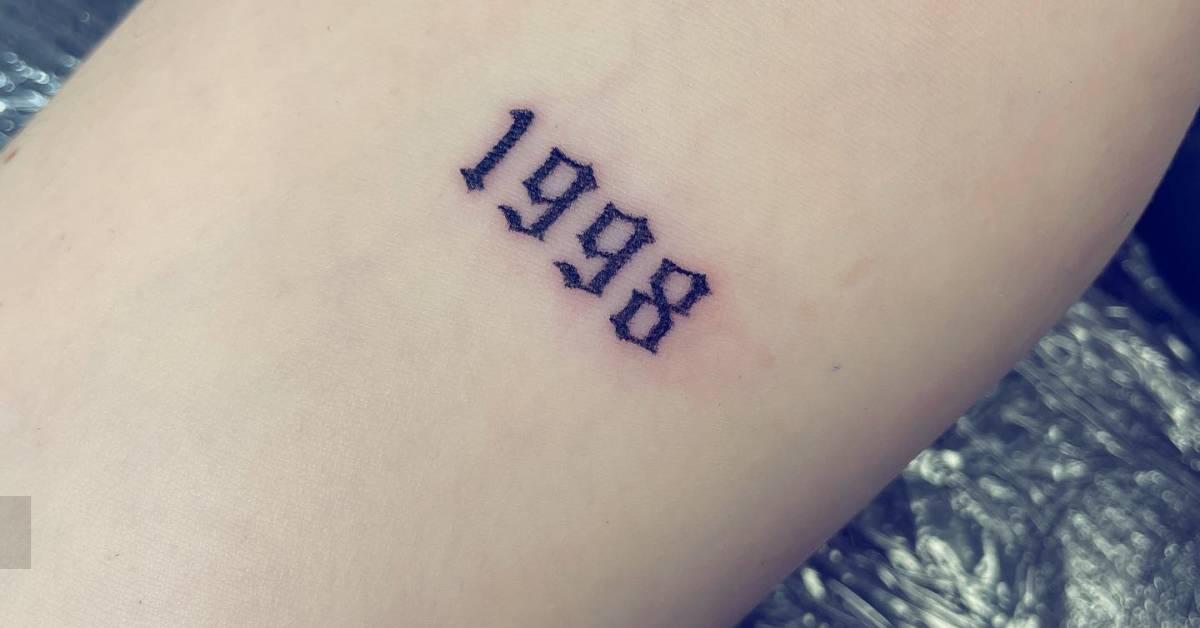 "1998" lettering tattoo located on the inner forearm.