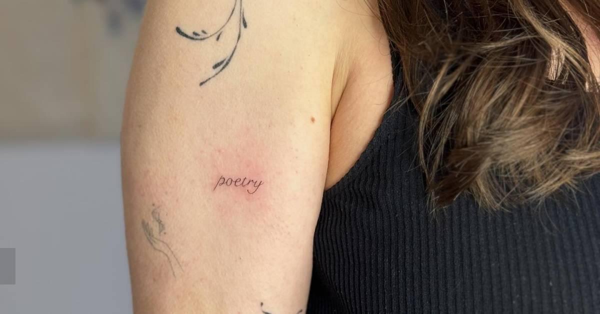 Tattoo of the word "poetry" located on the upper arm.