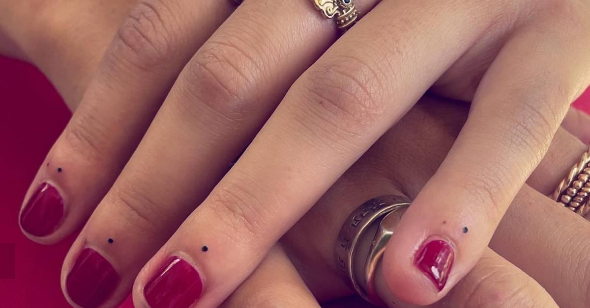 Minimalistic hand poked dots tattooed on the fingers.