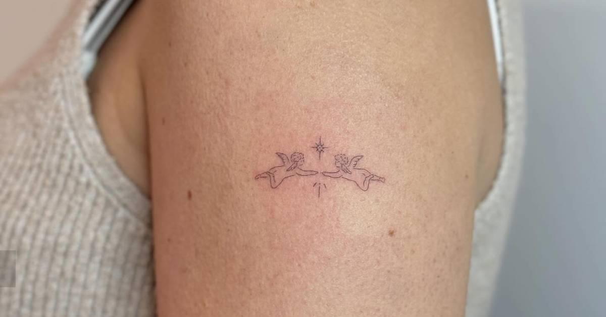 Tiny fine line cherubs tattooed on the upper arm.