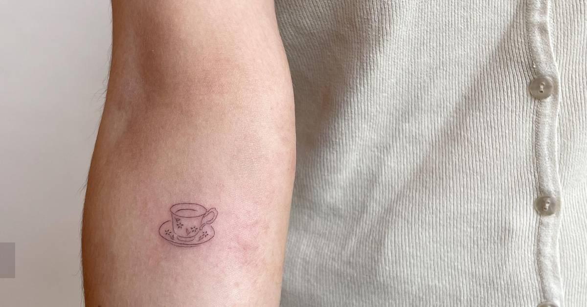 Fine line style little teacup tattoo placed on the