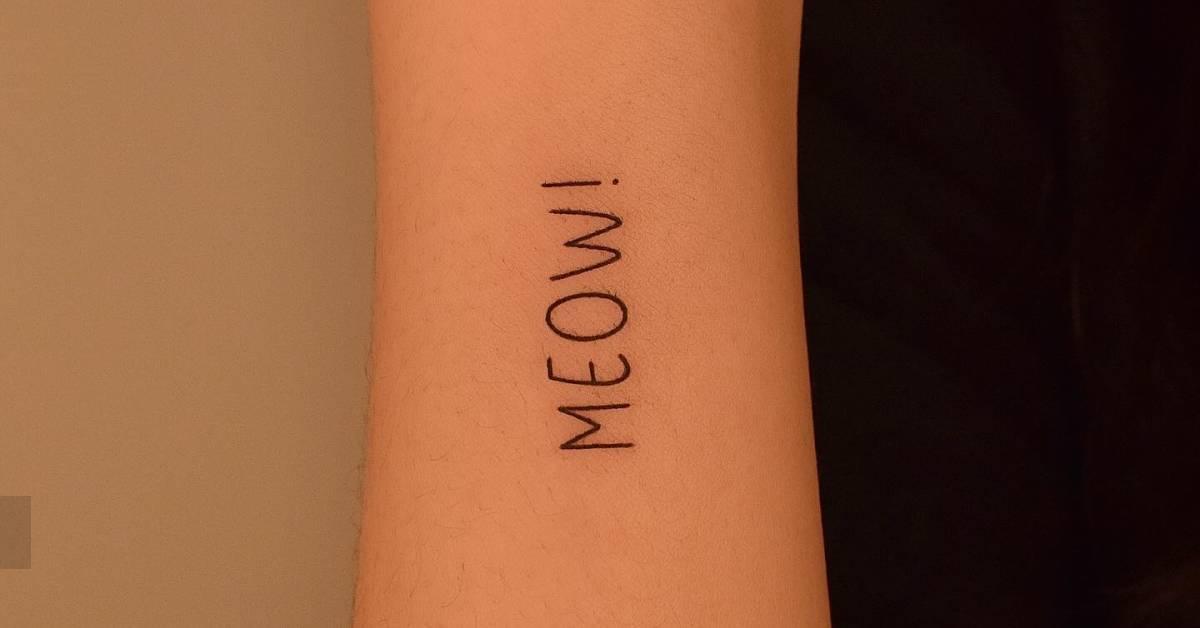 "Meow" lettering tattoo placed on the wrist.