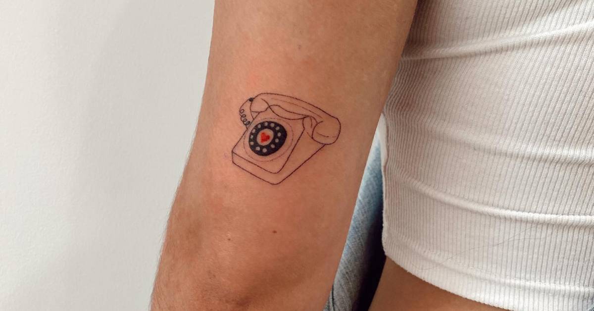 Hand poked telephone tattoo located on the tricep.