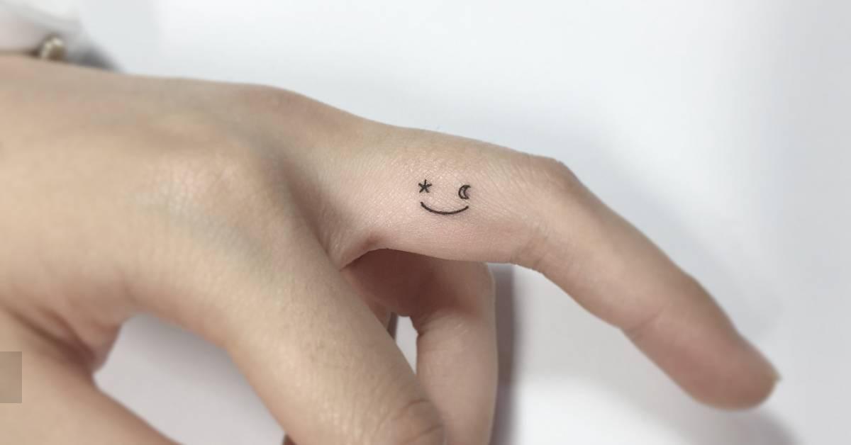 Smiley face with star and moon tattooed on the finger,