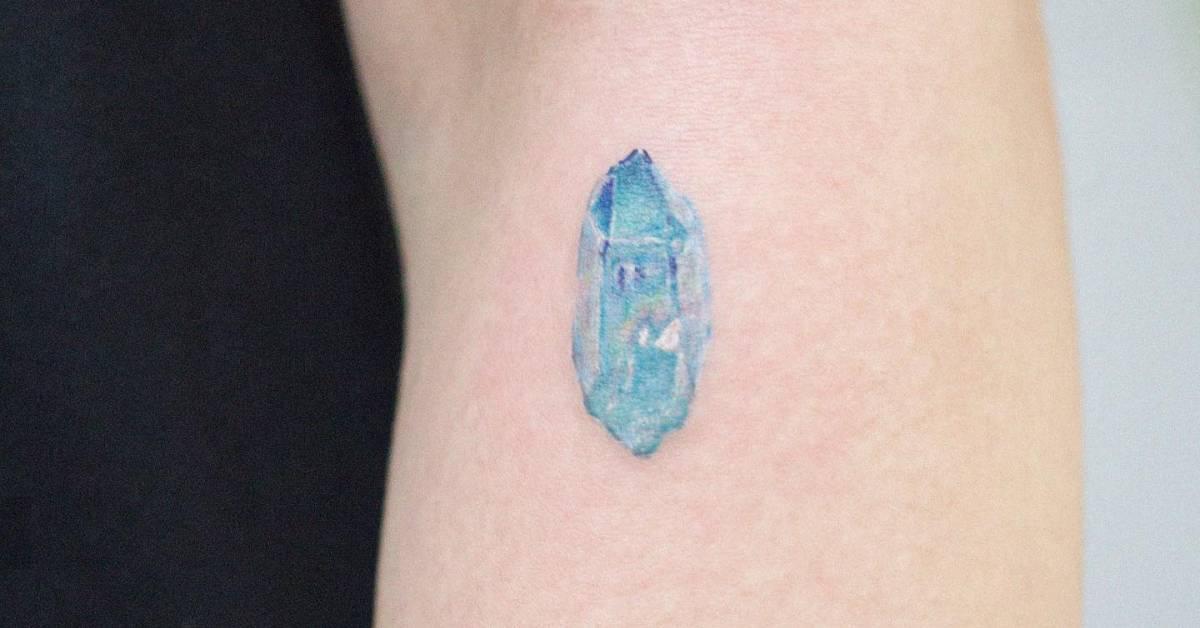 Aqua Aura Quartz tattooed on the forearm, watercolor