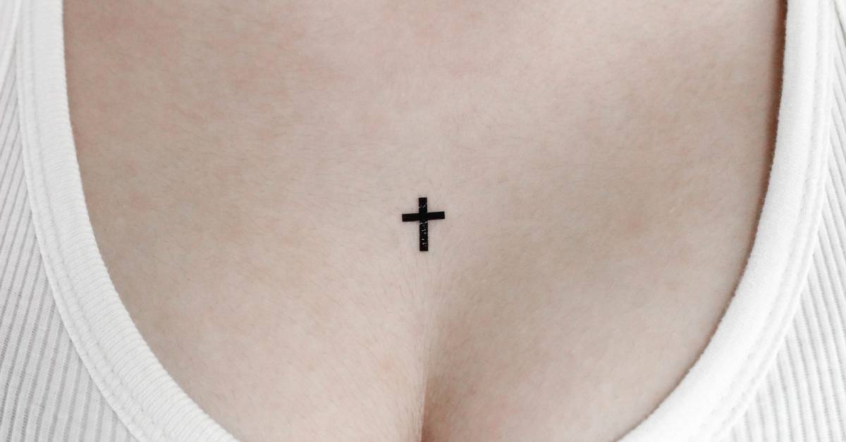 Small bold cross temporary tattoo placed on the chest.