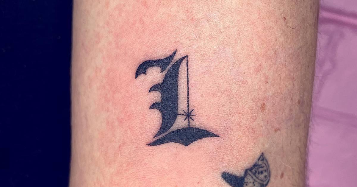Gothic letter "L" tattoo hand poked on the bicep.