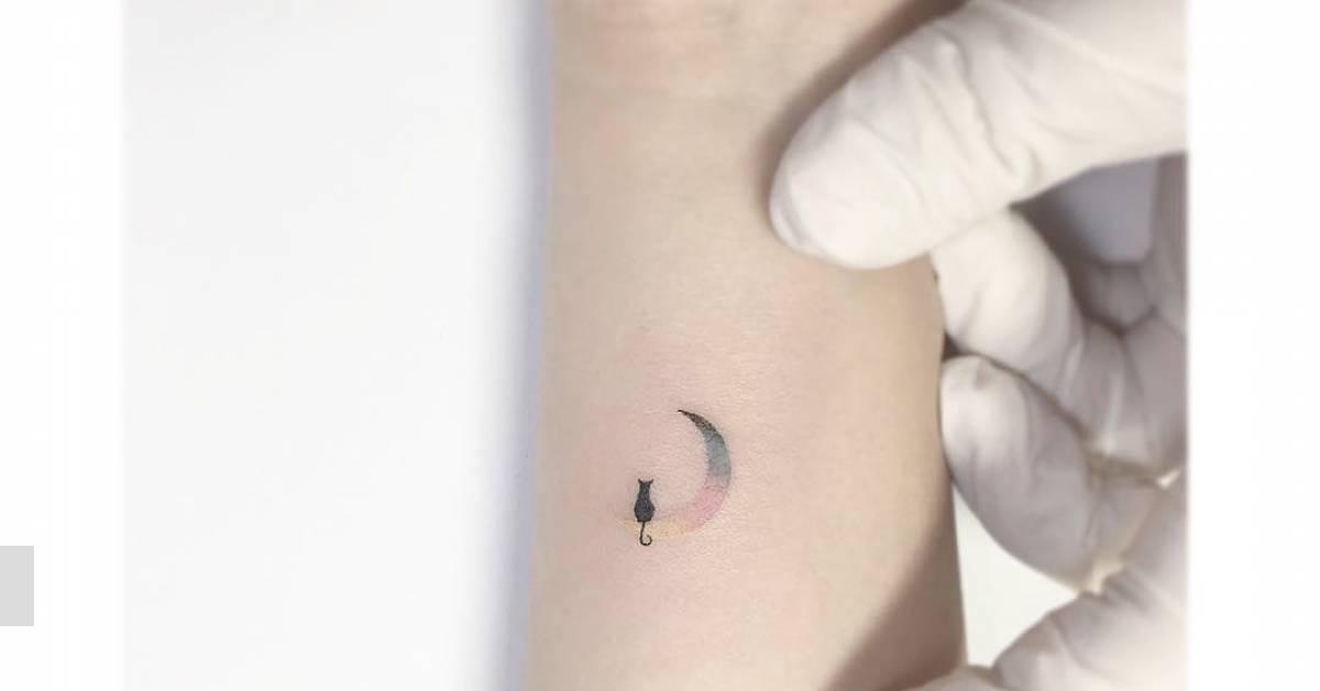 Cat and spectrum moon tattoo placed on the wrist.