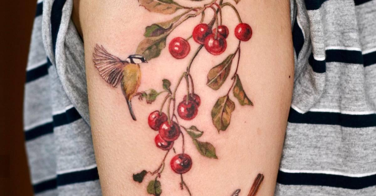 Cherries and robin birds tattoo done on the upper arm.