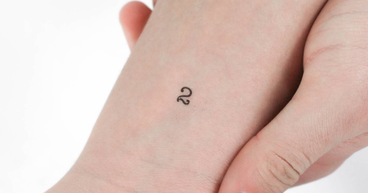 Tiny number "2" temporary tattoo located on the wrist.