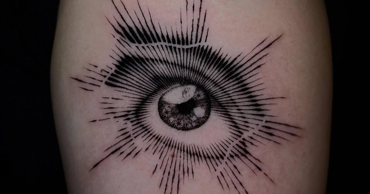 Engraving style eye tattoo located on the upper arm.