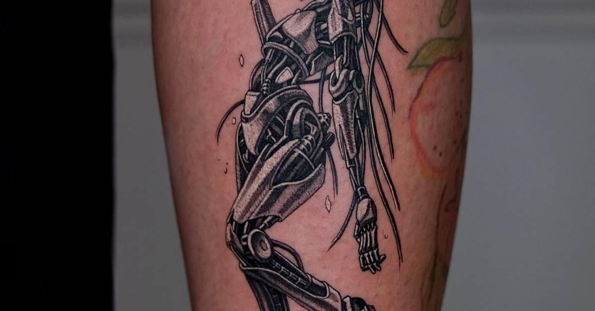 Comic style humanoid robot tattoo located on the calf.
