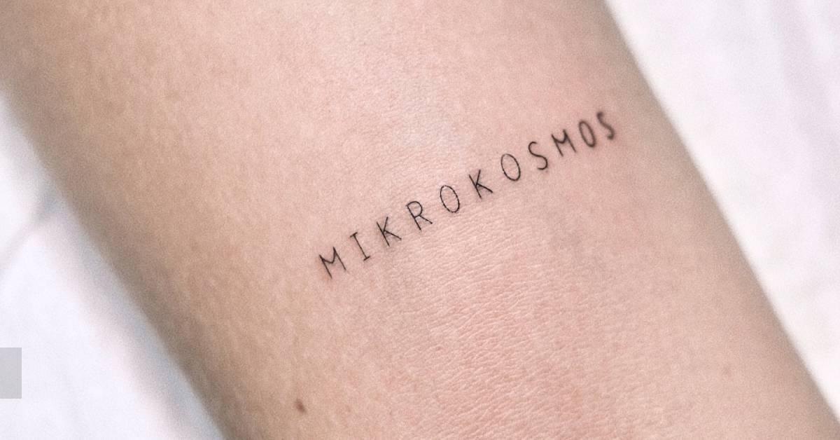 "Mikrokosmos" lettering tattoo located on the bicep.