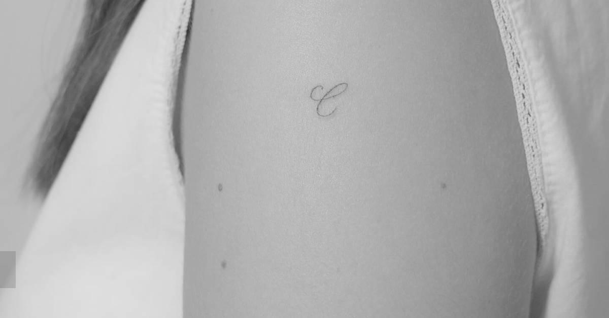 Tiny minimalistic letter "C" tattoo placed on the upper