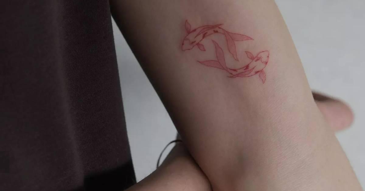 Two opposite fish tattoo in red ink located on the