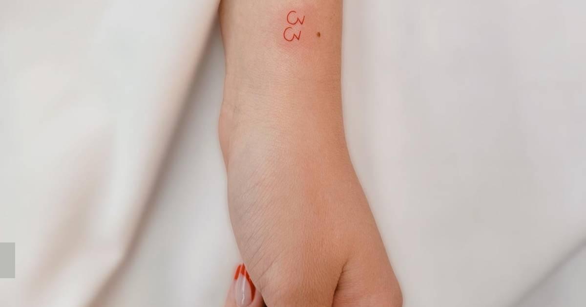 Tiny tattoo of the number "33" in red ink located on