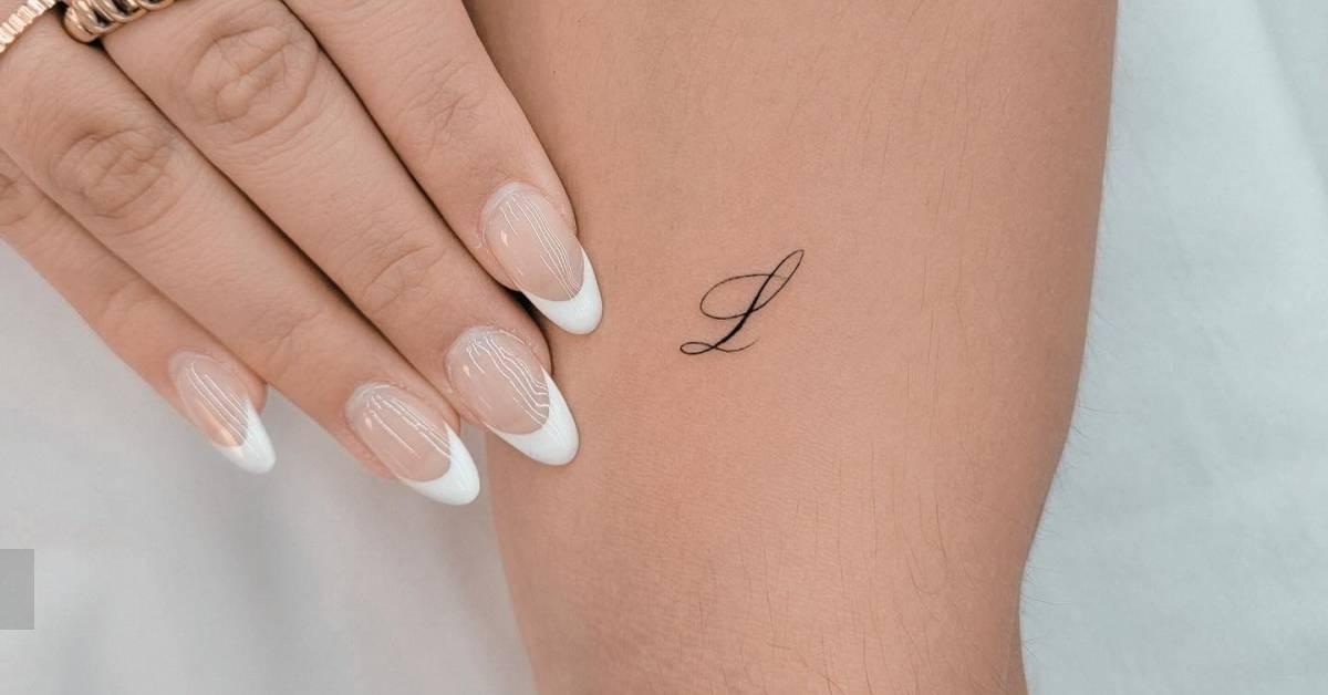 Little letter "L" tattoo placed on the upper arm.