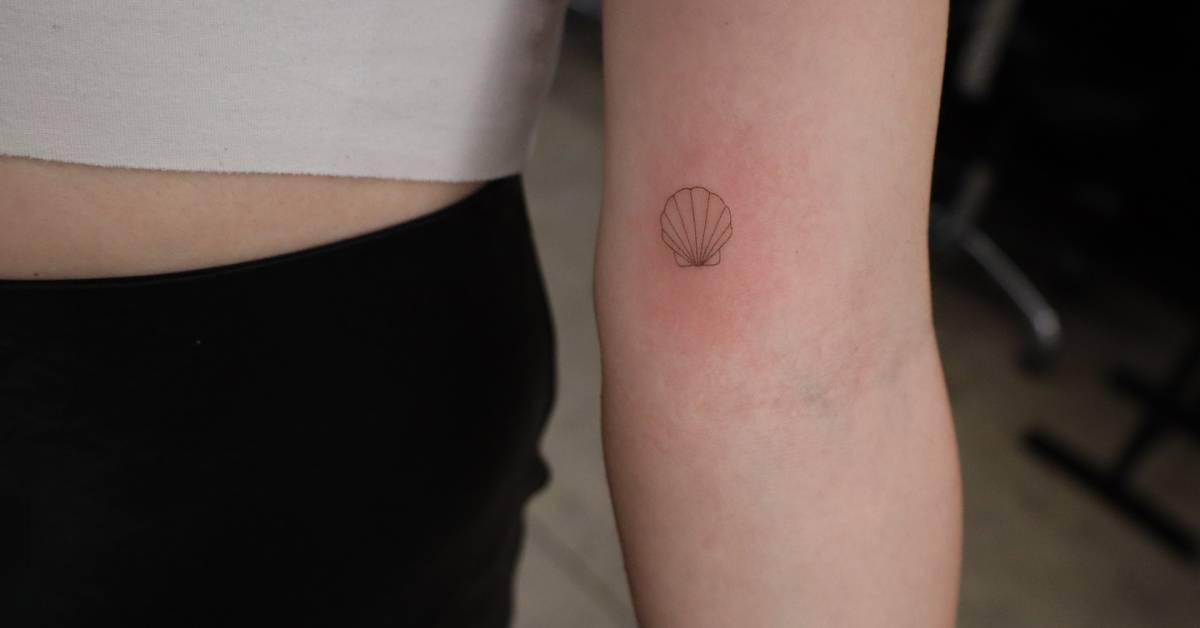 Fine line style scallop shell tattoo located on the