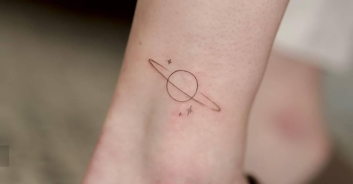 Fine line style Saturn and stars tattoo located on the