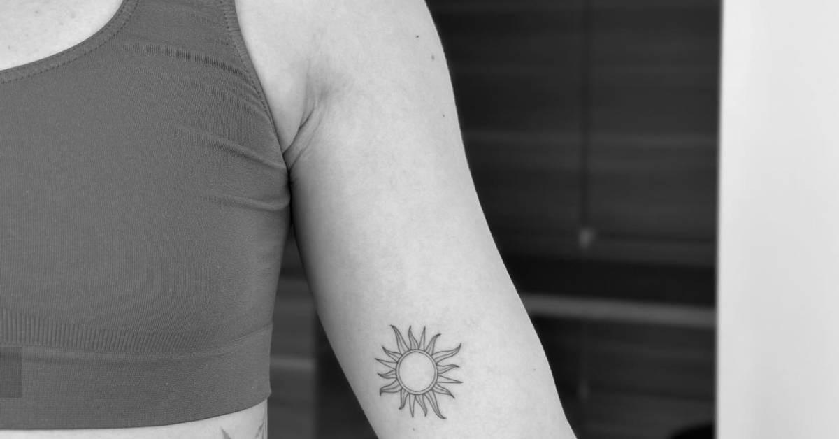 Fine line style sun tattoo placed on the inner arm.