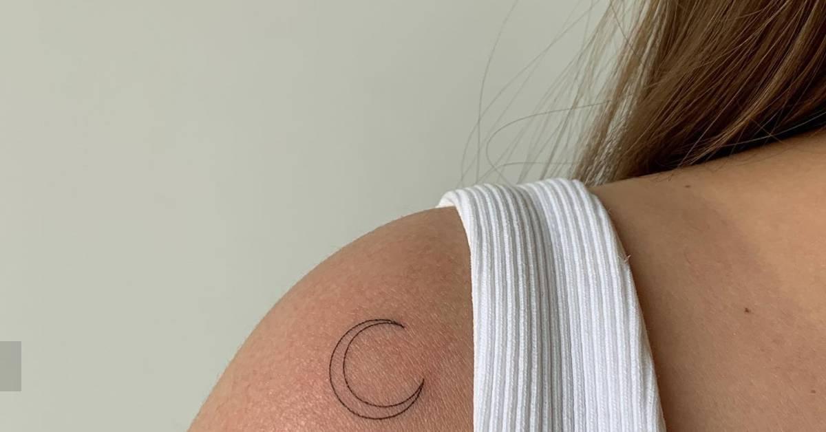 Fine line style crescent moon tattoo located on the
