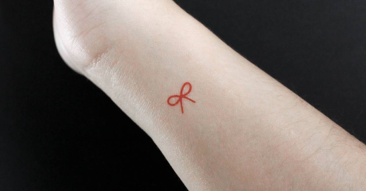 Tiny red bow temporary tattoo located on the wrist.