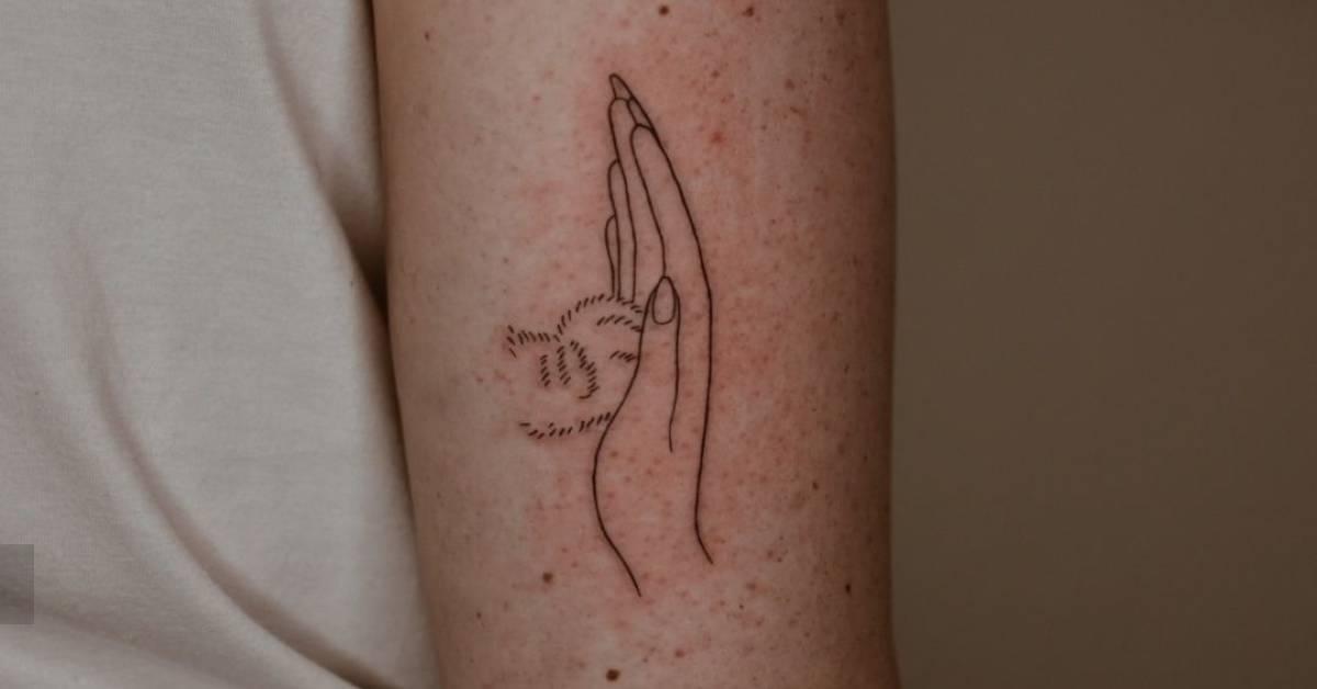 Fine line style dog high five tattoo located on the