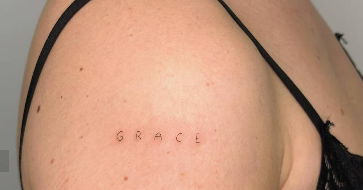 "Grace" lettering tattoo placed on the upper arm.