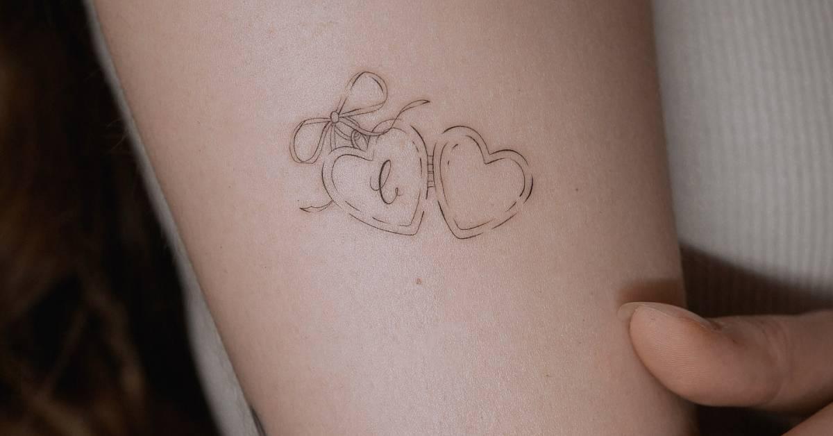 Fine line style heart pendant tattoo located on the