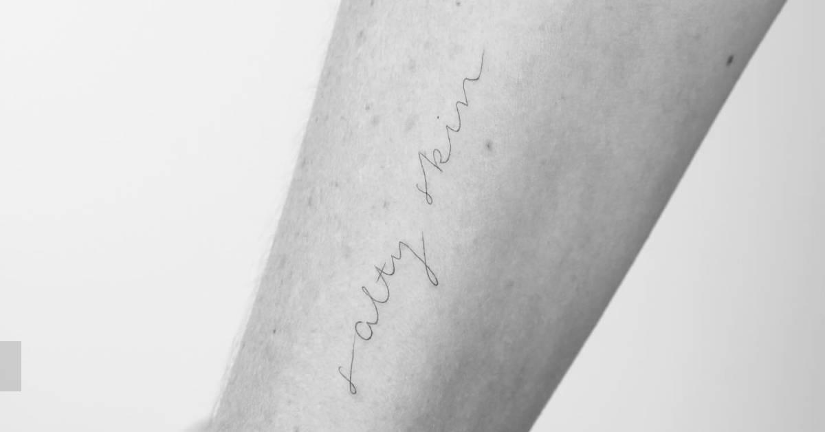 "Salty skin" lettering tattoo located on the wrist.