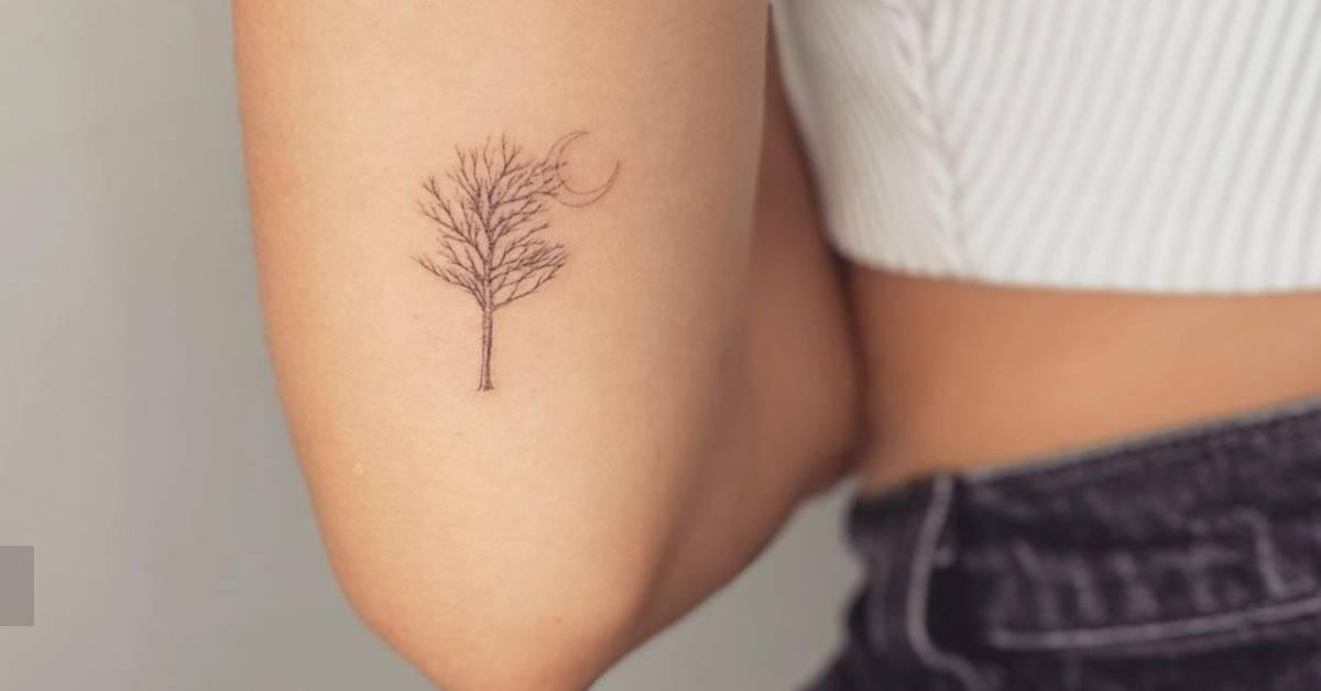 Single needle leafless tree and moon tattooed on the