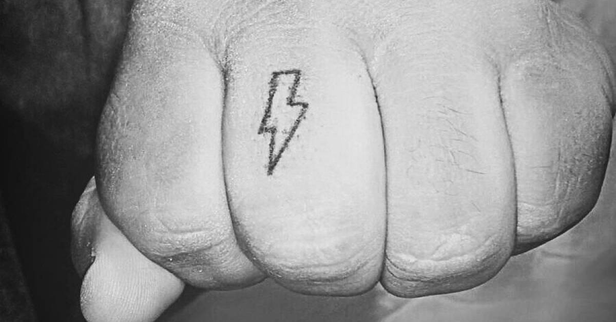 Tatuaje de un rayo situado en el dedo corazón de la