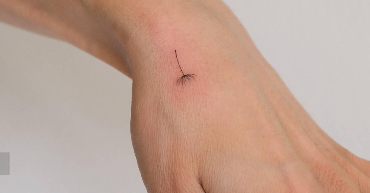 Minimalistic style dandelion seed tattoo located on the