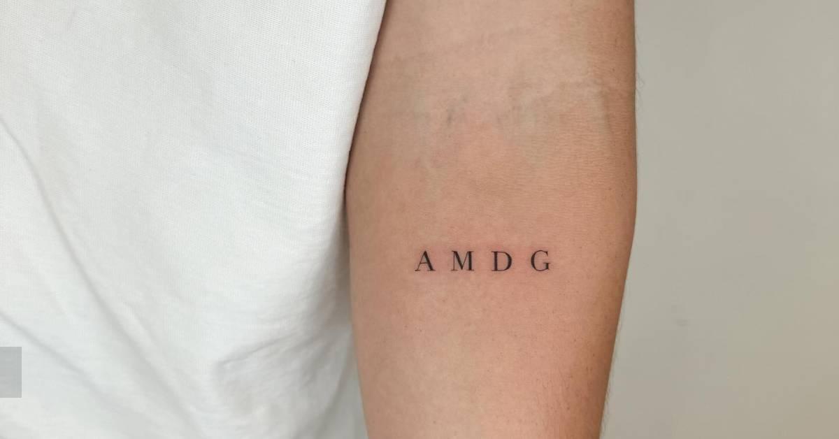Initials "AMDG" tattoo placed on the inner forearm.