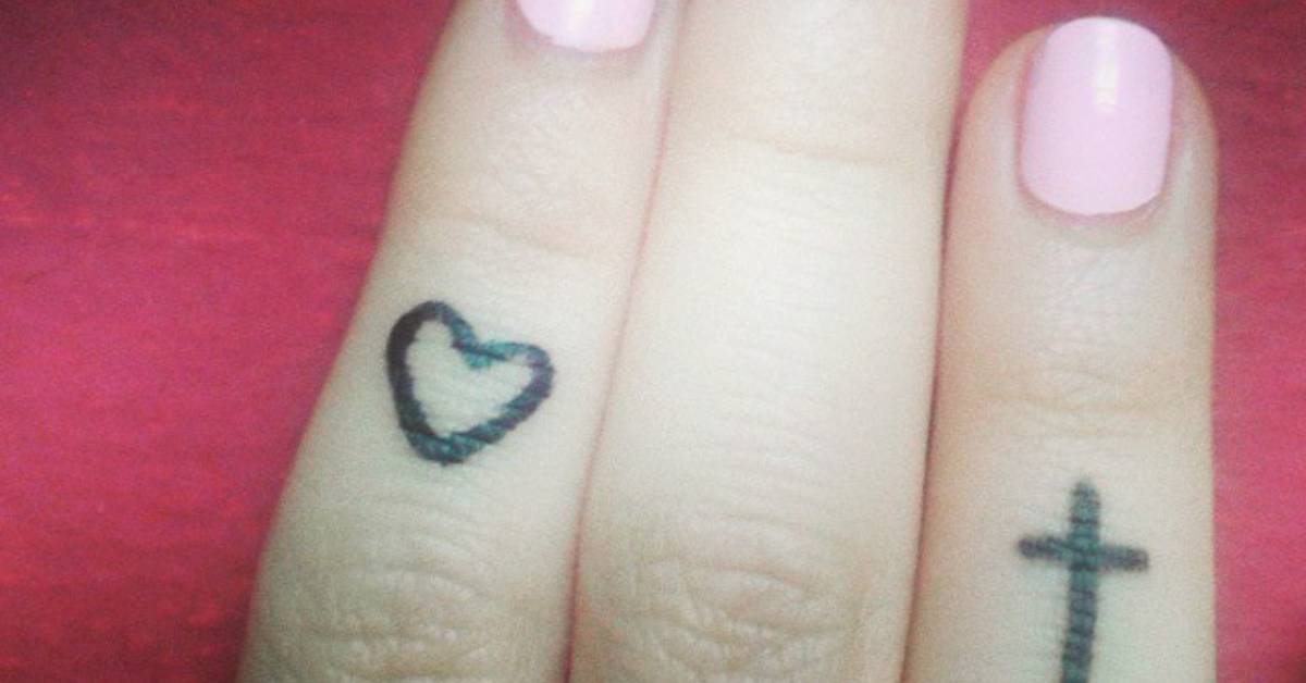 Finger tattoos of a heart and a christian cross.