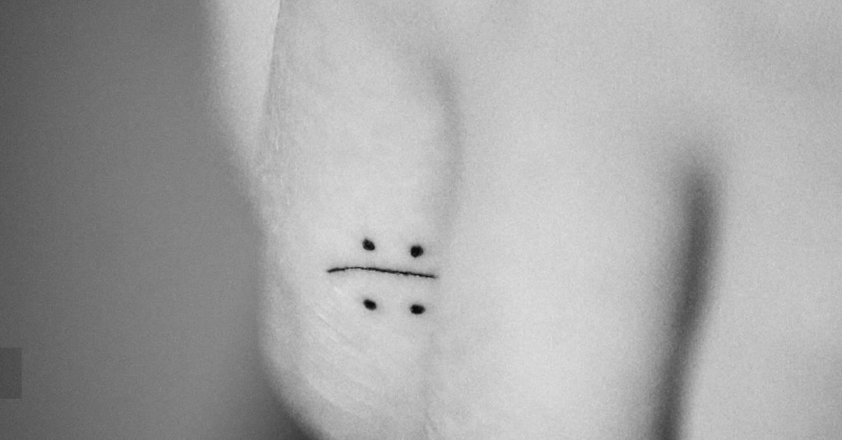 Minimalistic style happy sad face tattoo located on the