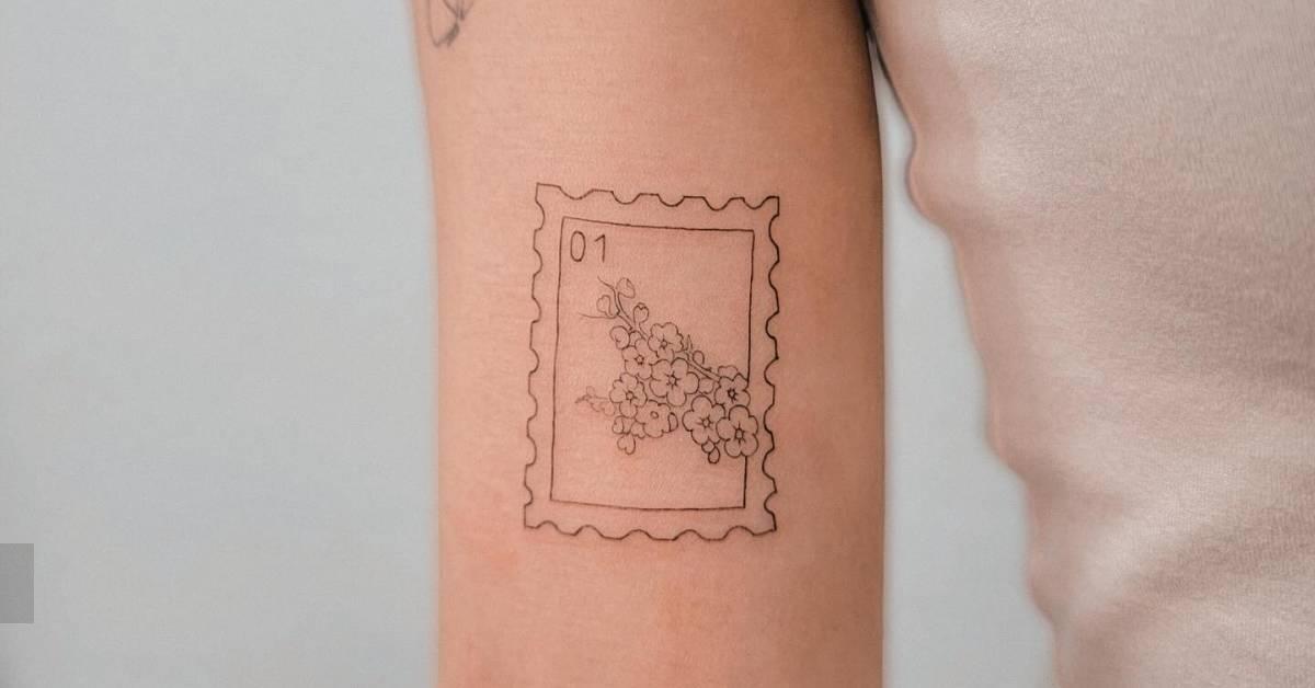 Fine line style flower stamp tattoo located on the