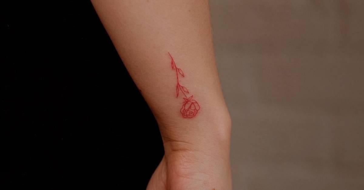 Fine line style red rose tattoo located on the wrist.